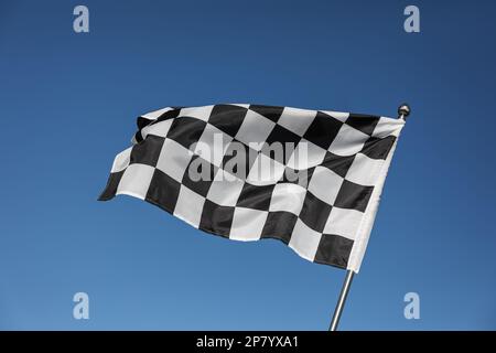 Checkered finish flag on light blue background Stock Photo - Alamy