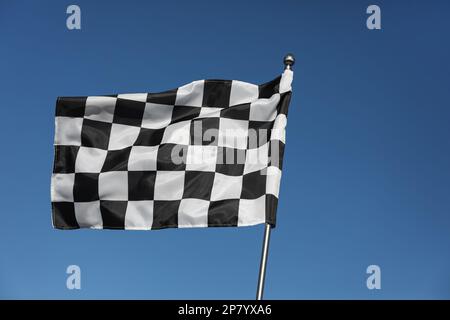 Checkered finish flag on light blue background Stock Photo - Alamy