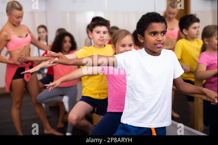 African boy practicing near ballet barre during group dance class Stock ...