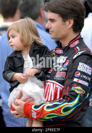 Jeff Gordon holds his daughter Ella Sophia as she tries on his racing ...