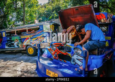 Mechanics fix the engine of a traditional jeepney. For decades ...