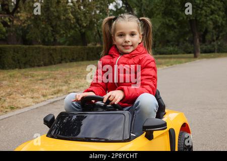 Cute little girl driving children's car outdoors Stock Photo - Alamy