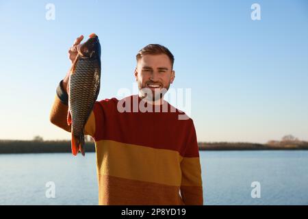Fisherman holding caught fish at riverside. Recreational activity Stock ...