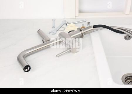 Plumbers tools and water tap ready for installation near sink on ...