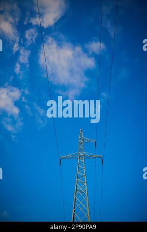 High voltage power cables suspended on a metal pole against a blue sky ...