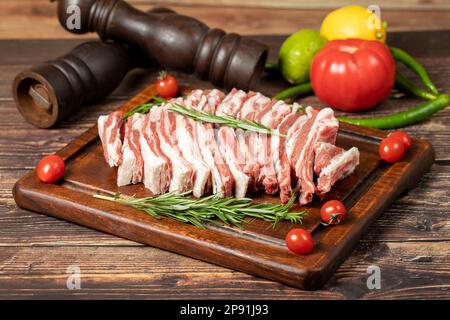 Fresh raw lamb spare ribs. Uncooked sliced lamb ribs on a wood serving ...