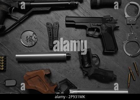 Flat lay composition with different guns on dark table Stock Photo - Alamy