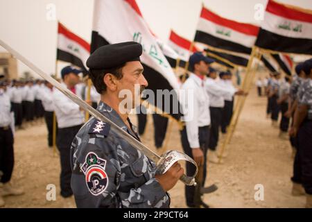 Iraqi police graduate stands at attention as national flags flutter ...