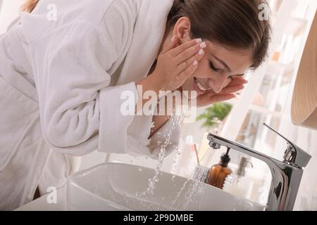 Beautiful teenage girl washing face with cleansing foam in bathroom ...
