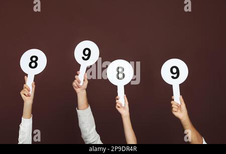Panel of judges holding different score signs at table on beige ...