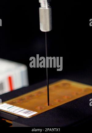 A robotic arm puts a drops of DNA-bearing solution on a slide during a ...