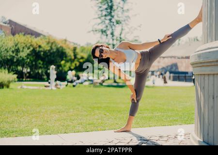 Flexible young woman shows splits by putting her foot on a pole Stock ...