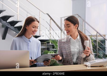 Female receptionists working at desk in hotel Stock Photo - Alamy