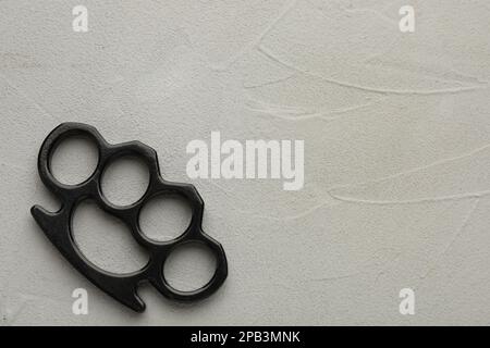 Black brass knuckles on grey background, top view. Space for text Stock ...