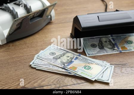 Modern currency detector with dollar banknotes and magnifying glass on ...