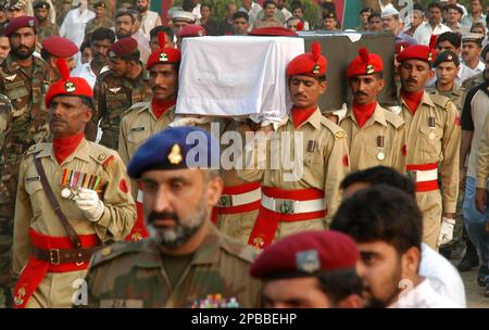 Pakistani soldiers carry a dead body recovered from the rubble at the ...