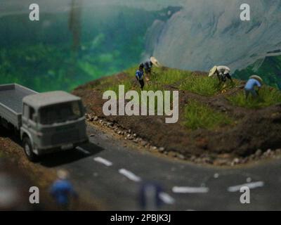 a miniature diorama of a rice field and a road as well as several ...
