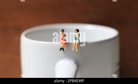 Miniature figures of 2 women talking over glasses. discussion concept ...