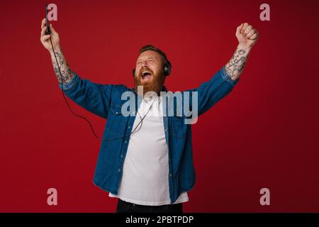 Ginger white man singing and dancing while listening music isolated ...