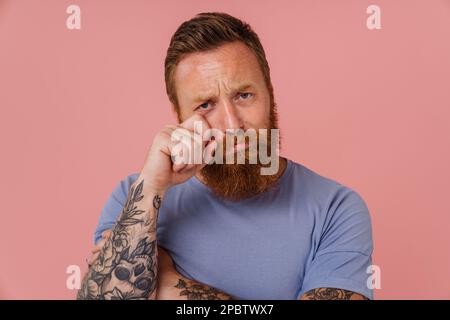 Ginger sad man with beard crying while wiping his tears isolated over ...