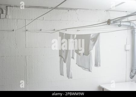 White pajamas or clothing hanging from drying lines inside communal ...