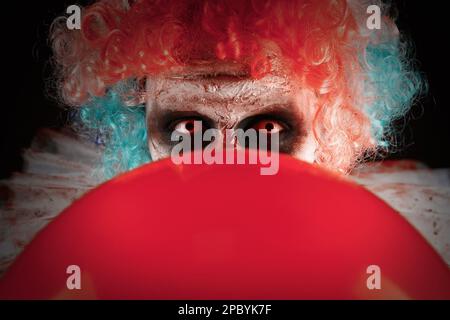Terrifying clown with red air balloon on black background. Halloween ...