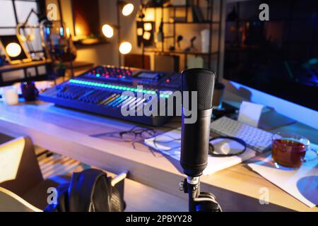 Microphone near table with professional mixing console in radio studio ...