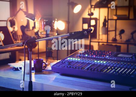Microphone near table with professional mixing console in radio studio ...