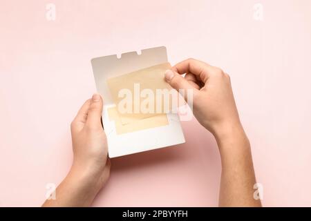 Woman with package of oil blotting tissues on violet background, top ...