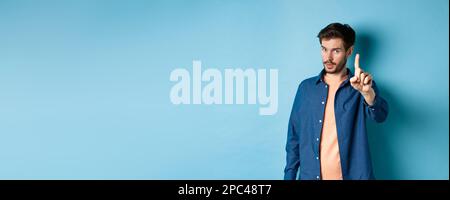 Image of young man give warning, teaching a lesson, raising one finger ...