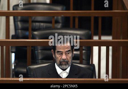 Saddam Hussein sits in court as Hussein Rashid Mohammed, back left, and ...
