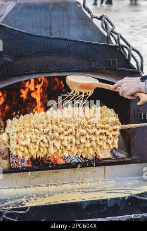 Preparing Lithuanian tree cake, šakotis or baumkuchenas, Polish sękacz ...