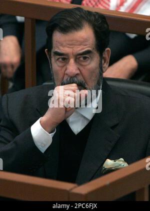 Saddam Hussein sits in court as Hussein Rashid Mohammed, back left, and ...