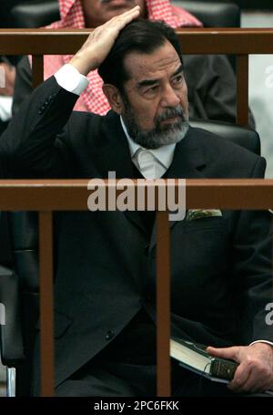 Saddam Hussein sits in court as Hussein Rashid Mohammed, back left, and ...