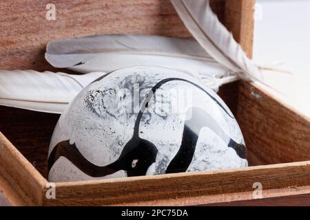 structured black and white glass sphere inside a wooden box isolated on ...