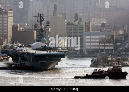 The USS Intrepid aircraft carrier is pulled by tugboats from its berth ...