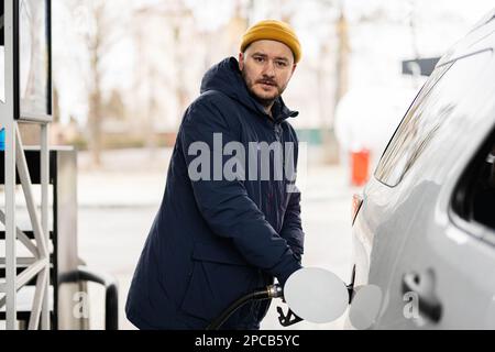 Man refueling his american SUV car at the gas station in cold weather ...