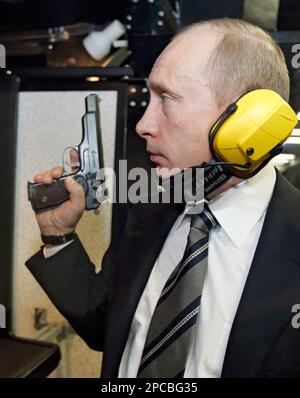 President Vladimir Putin wears headphones as he tests a pistol in a ...