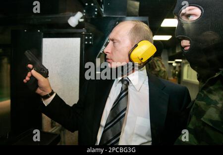 President Vladimir Putin wears headphones as he tests a pistol in a ...