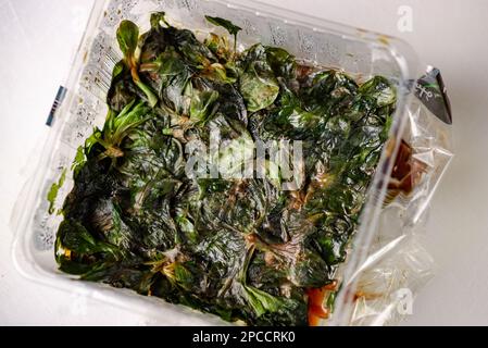 Spoiled mix of different salads in plastic packaging. Expired shelf ...