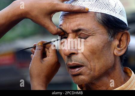 An Indian Muslim gets his eyes lined with a black ointment called Surma ...