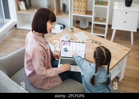 Pretty girl with a laptop on her knees working or studying indoors ...