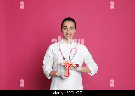 Doctor demonstrating model of female reproductive system on light blue ...