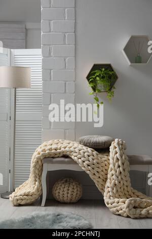 Indoor bench with soft chunky knit blanket and pouf in room. Interior ...