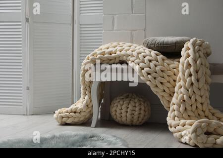 Indoor bench with soft chunky knit blanket, cushion and pouf in room ...