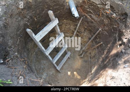 Digging a deep round hole with sewer line, drain pipe outlet for a ...