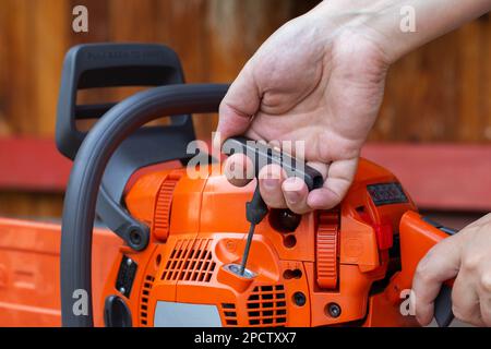 The process of starting a chainsaw. A male worker pulls the starting ...
