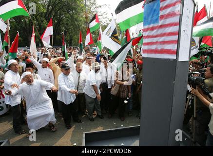 Muslim protesters throw wads of tissue paper at a wooden pillar ...