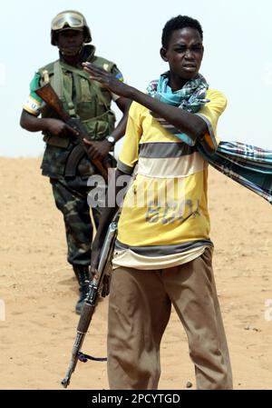 A Sudan Liberation Army, SLA fighter passes by an African Union APC ...