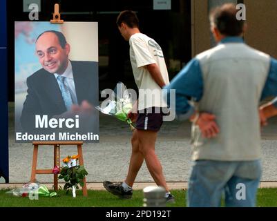 A man places flowers at the base of a photograph of Edouard Michelin ...